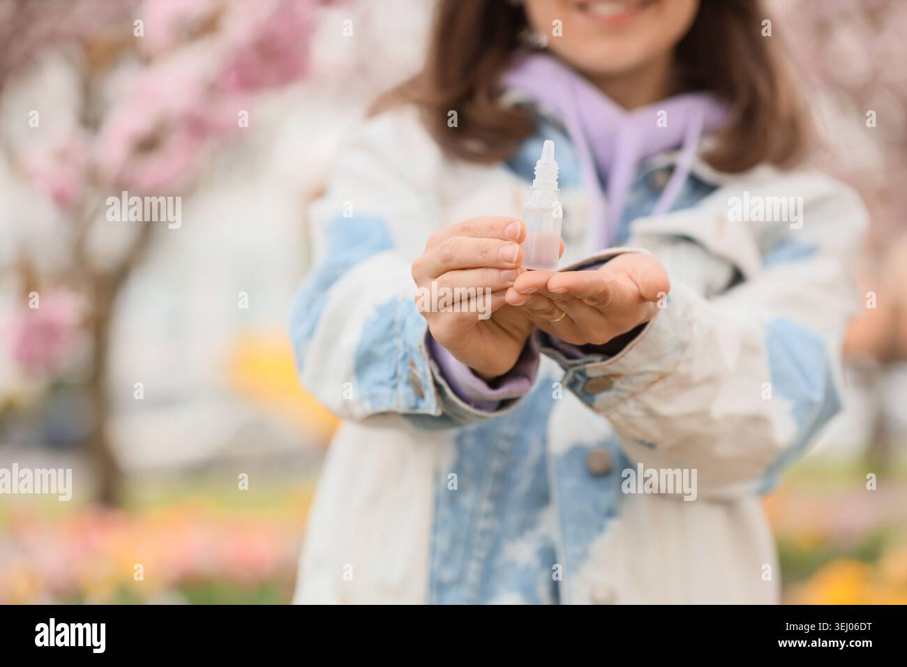 Allergic young woman with eye drops in park on spring day, closeup ...