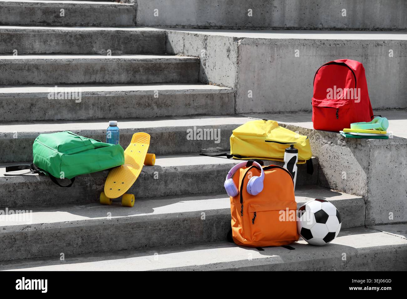 Colorful backpacks with water bottles, skateboard and soccer ball on ...