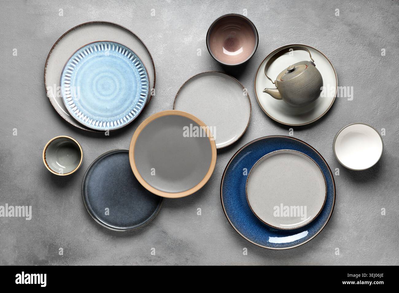 Different plates with bowls and teapot on grey grunge background Stock ...