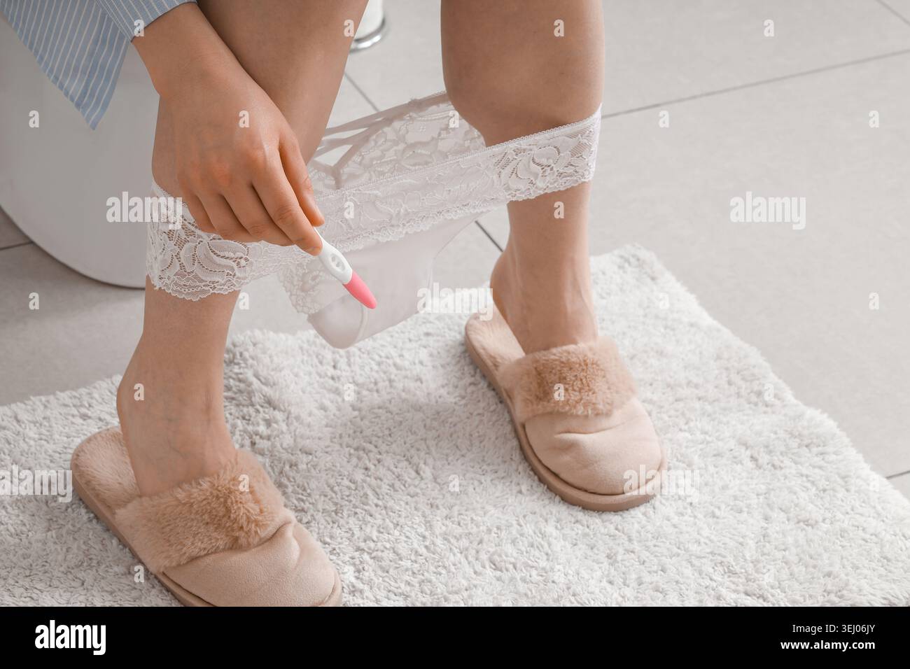 Woman with pregnancy test sitting on toilet bowl in restroom, closeup ...