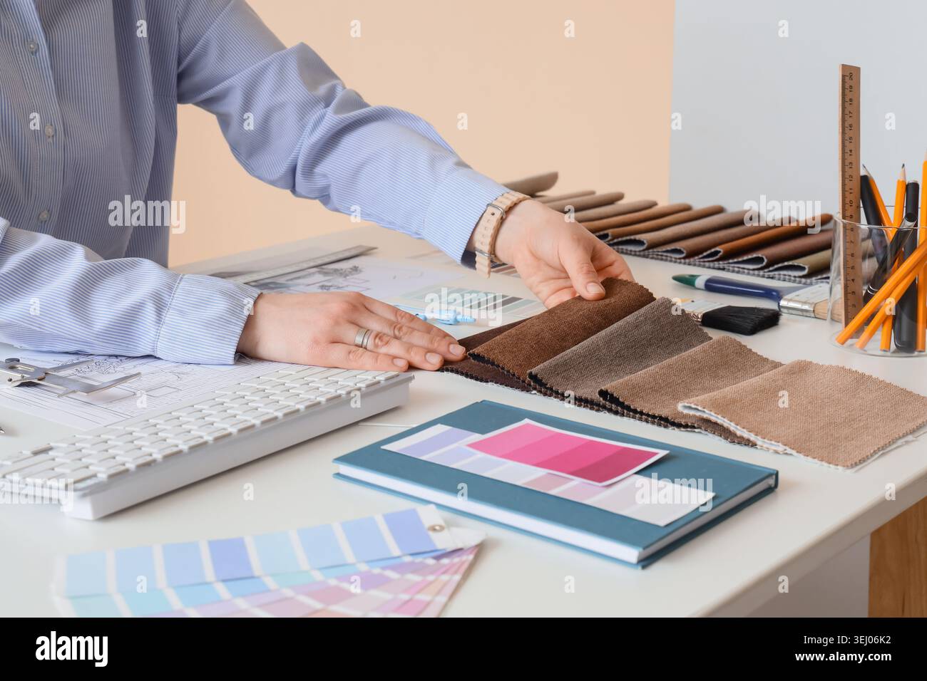Female interior designer with fabric samples working at table in office ...