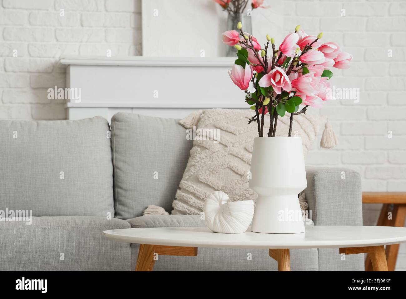 Vase with artificial magnolia flowers and decor on table in living room ...