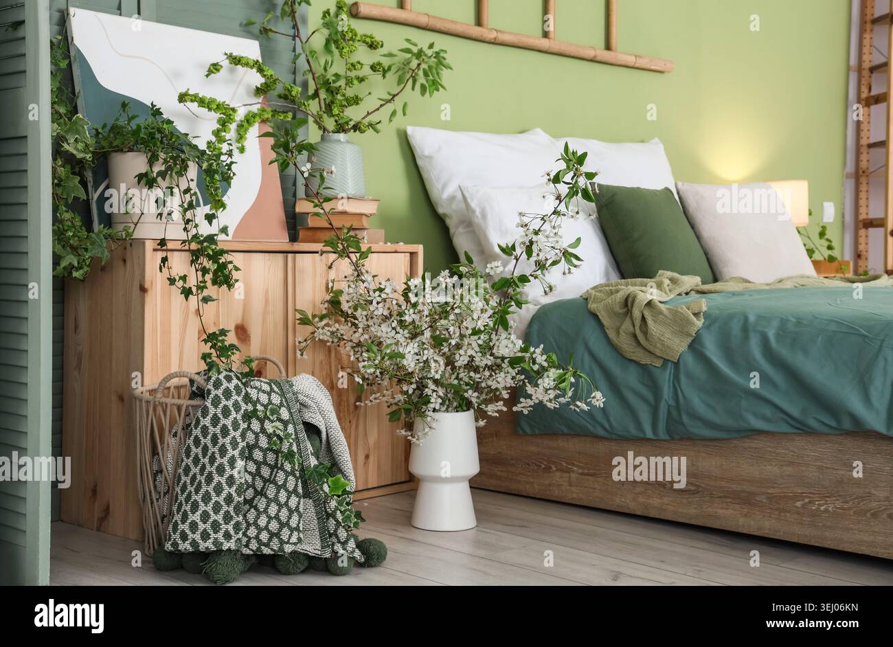 Interior of stylish bedroom with chest of drawers, basket, blanket and ...