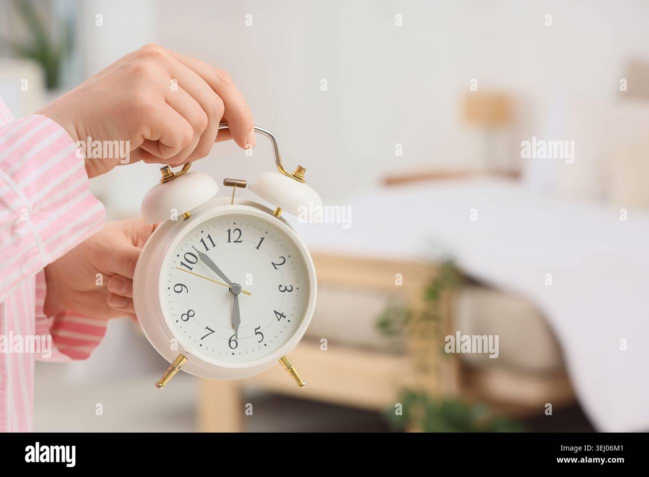 Female hands changing alarm clock for daylight saving time in bedroom ...