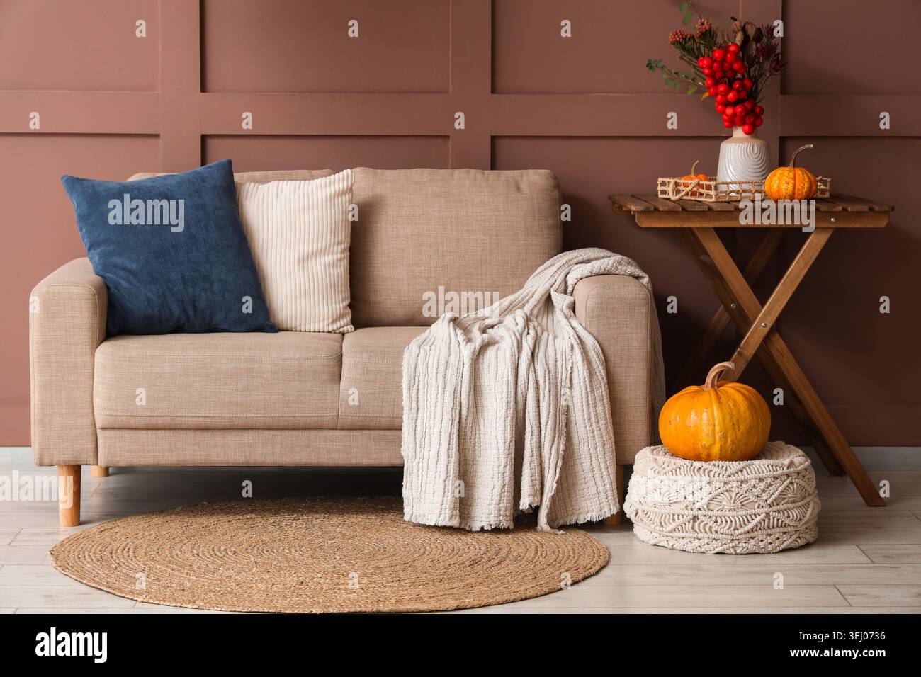 Comfortable sofa, table, pouf and autumn decor in interior of living ...