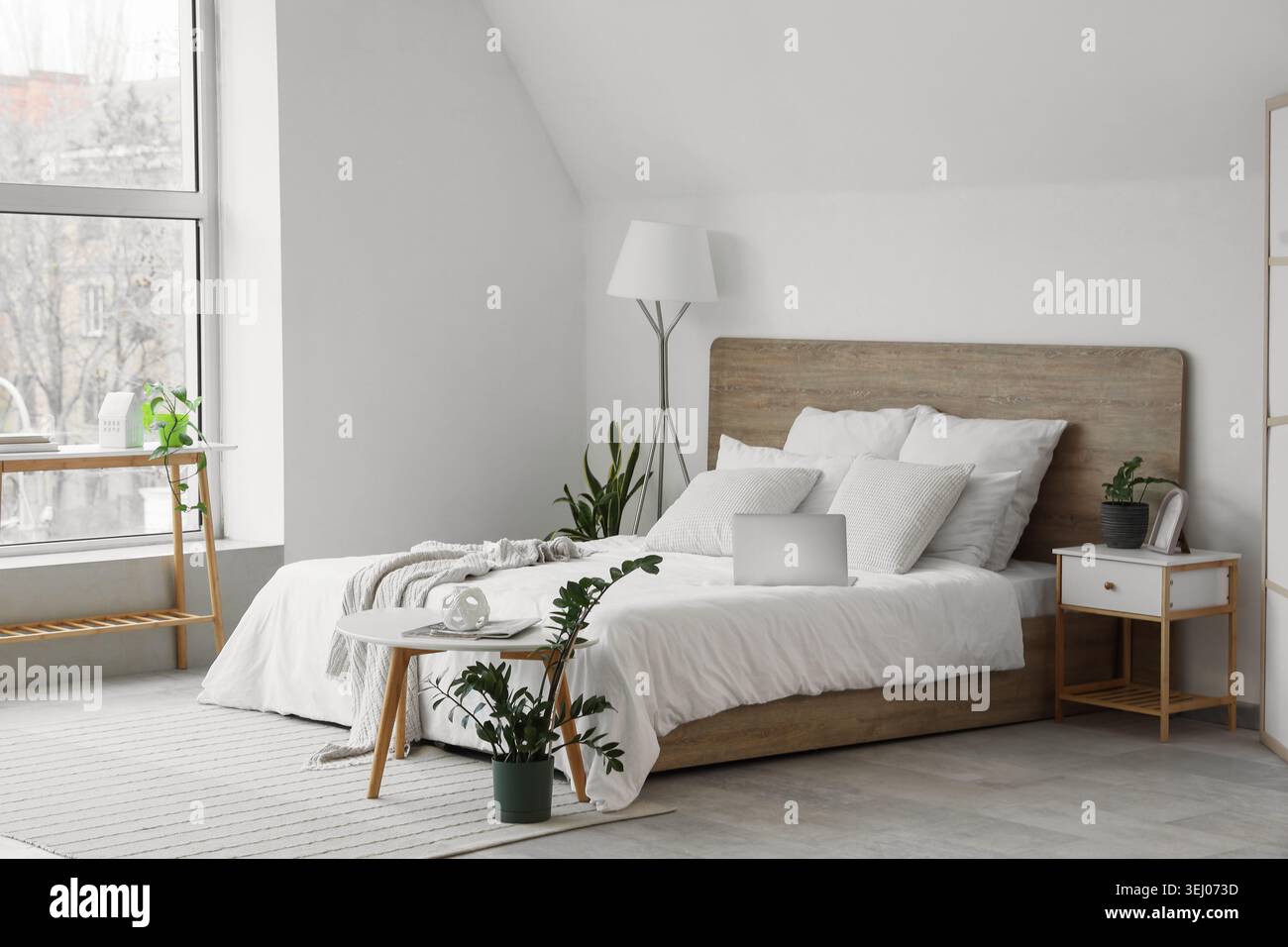 Interior of light bedroom with lamp, tables and plants Stock Photo - Alamy