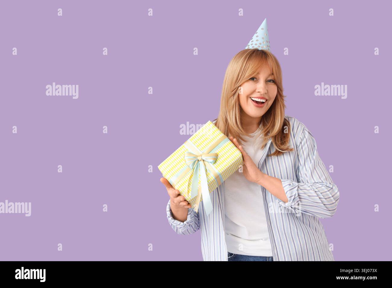 Beautiful woman in party hat with Birthday gift on lilac background ...
