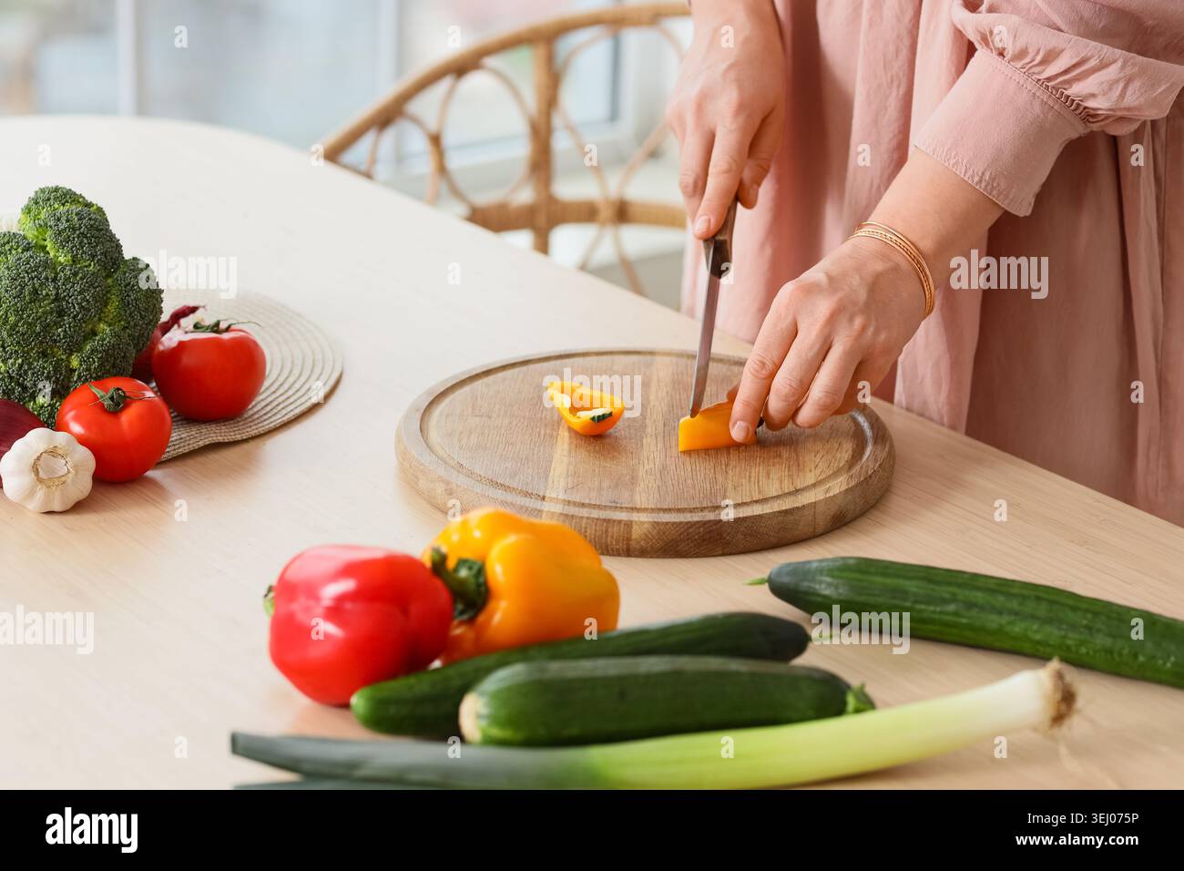 Woman cutting pepper at table in kitchen, closeup Stock Photo - Alamy