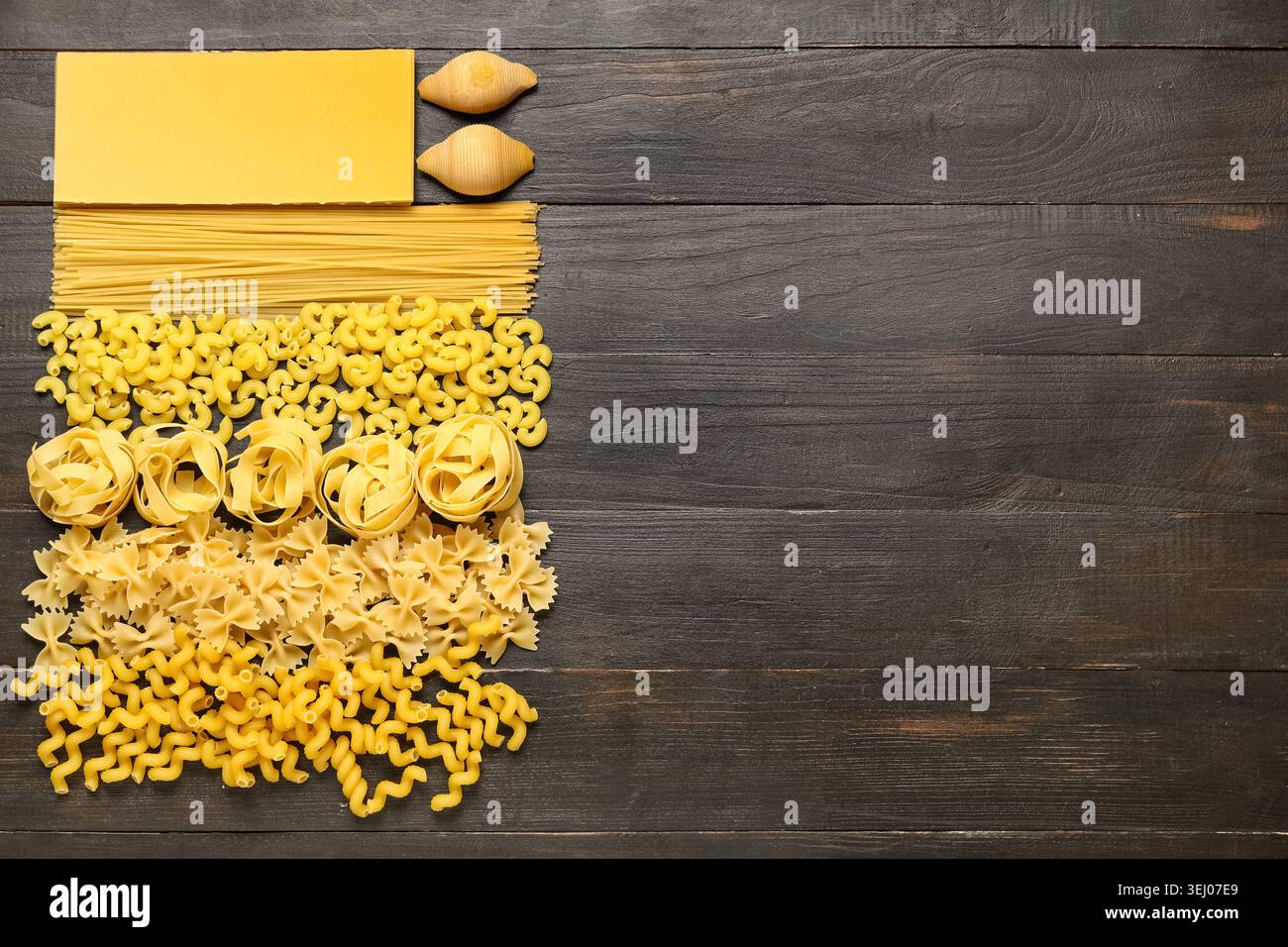 Composition with different types of raw pasta on black wooden ...