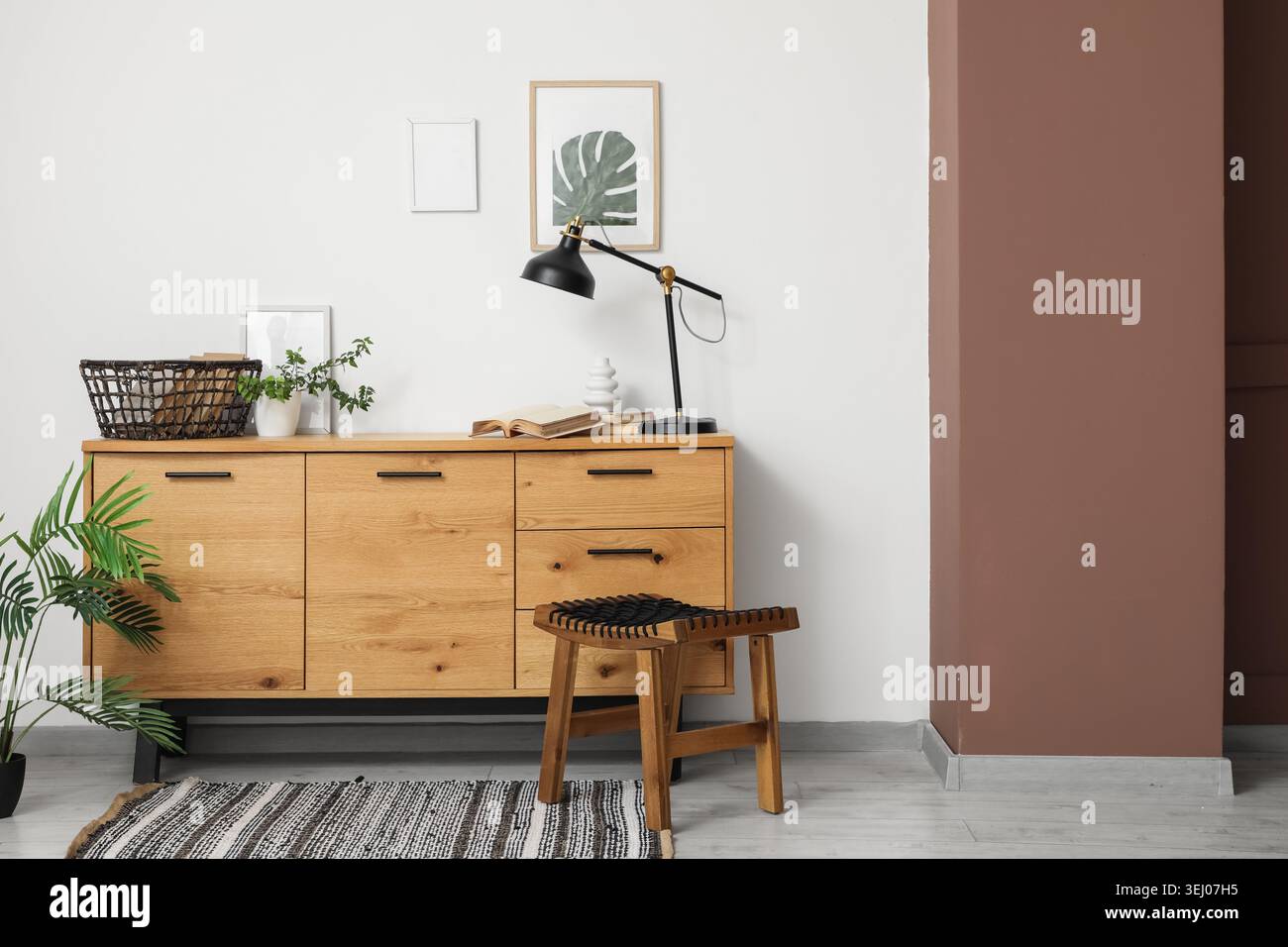 Interior of living room with chest of drawers, stool and houseplant ...