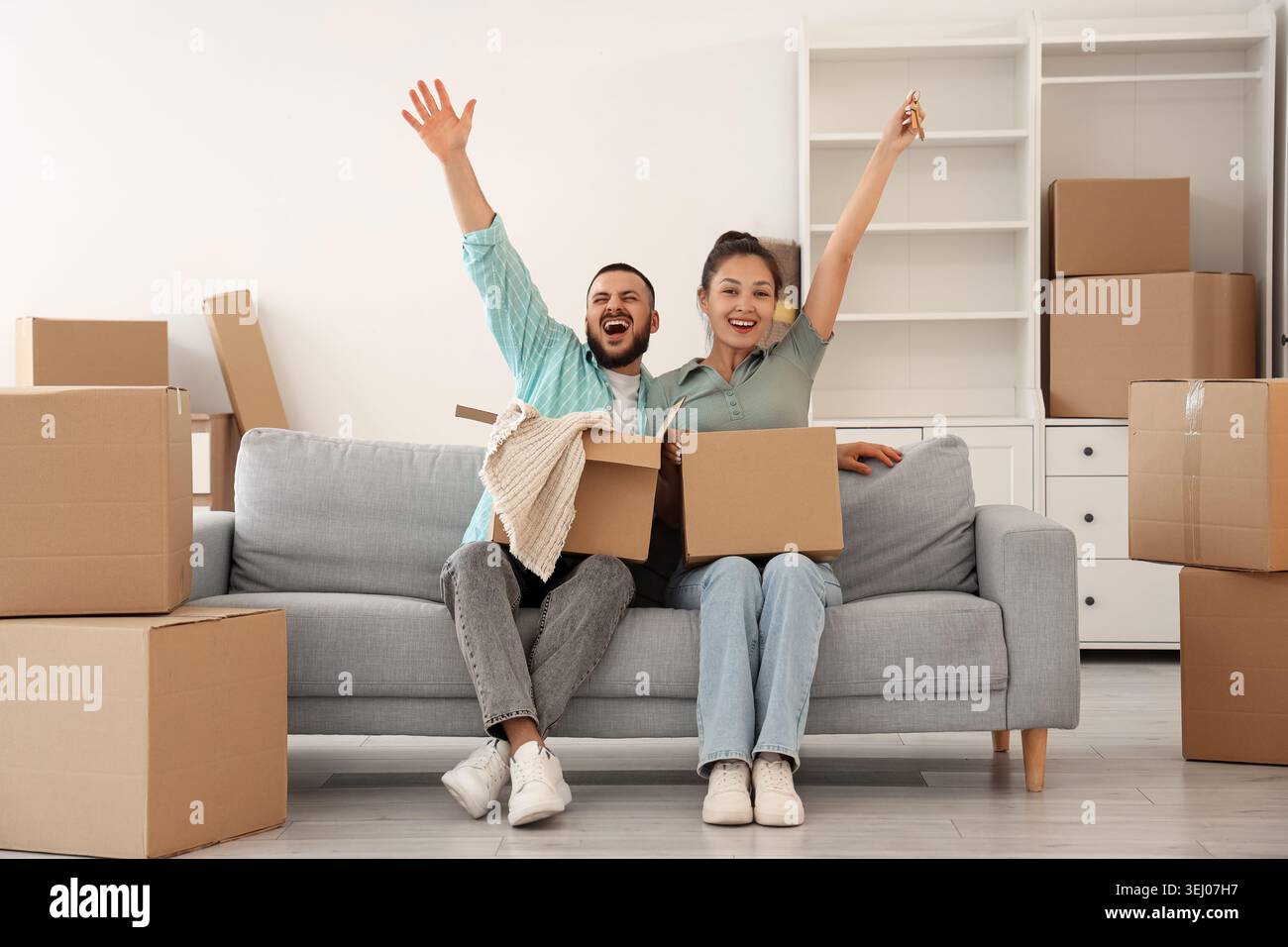 Happy young couple with key from their new house and boxes sitting on ...