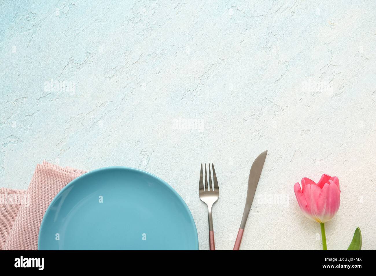 Beautiful table setting with pink tulip flower on light blue background ...