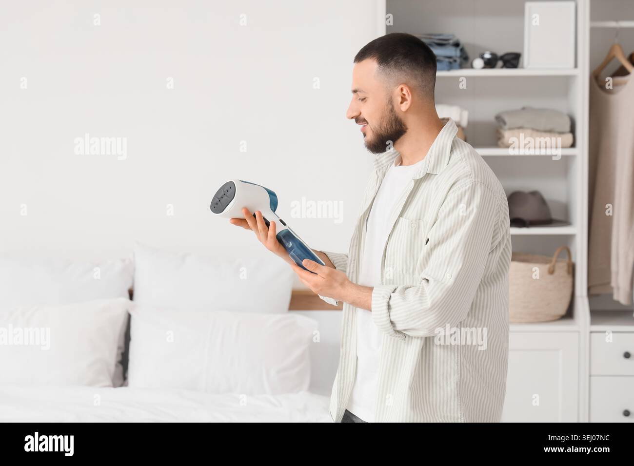 Young man with steamer in bedroom Stock Photo - Alamy
