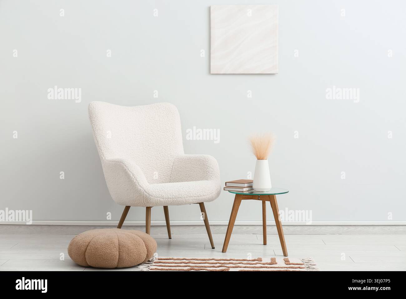 Comfortable armchair with soft pouf and table near white wall in living ...