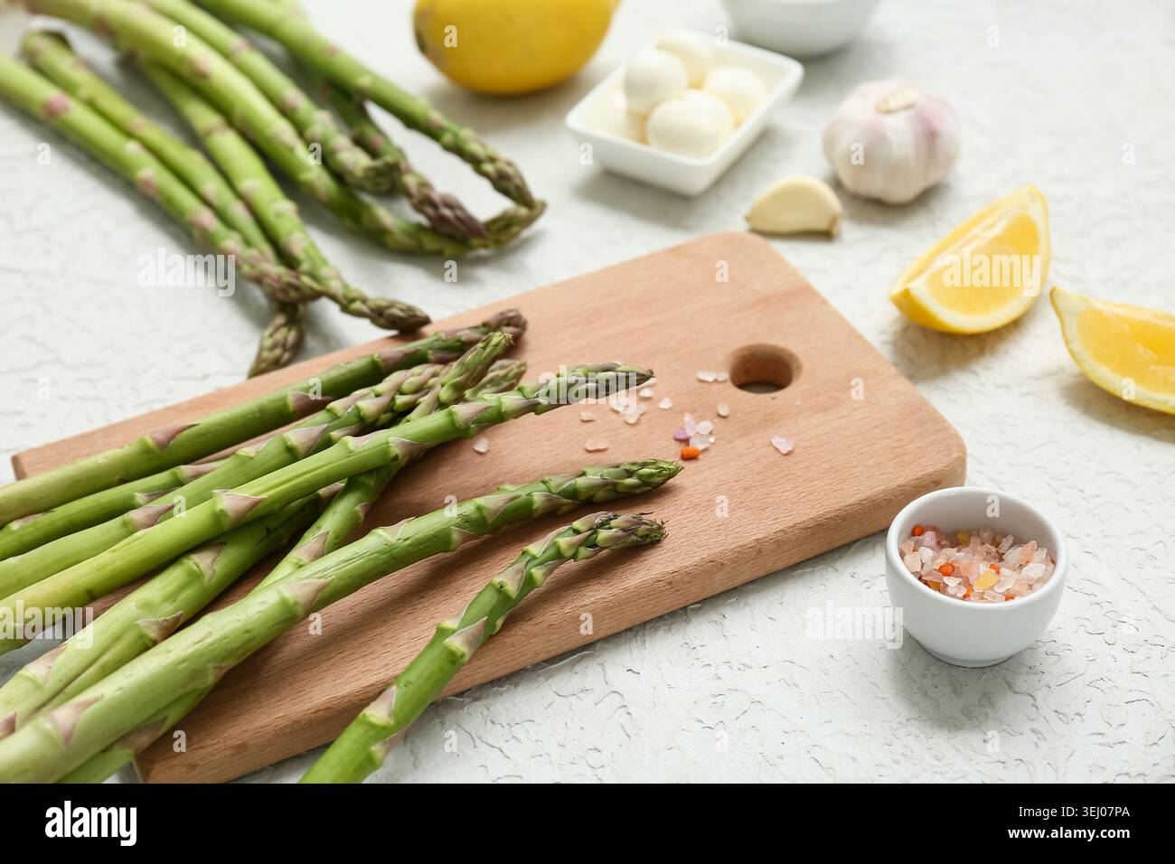 Wooden board with fresh green asparagus and different ingredients on ...