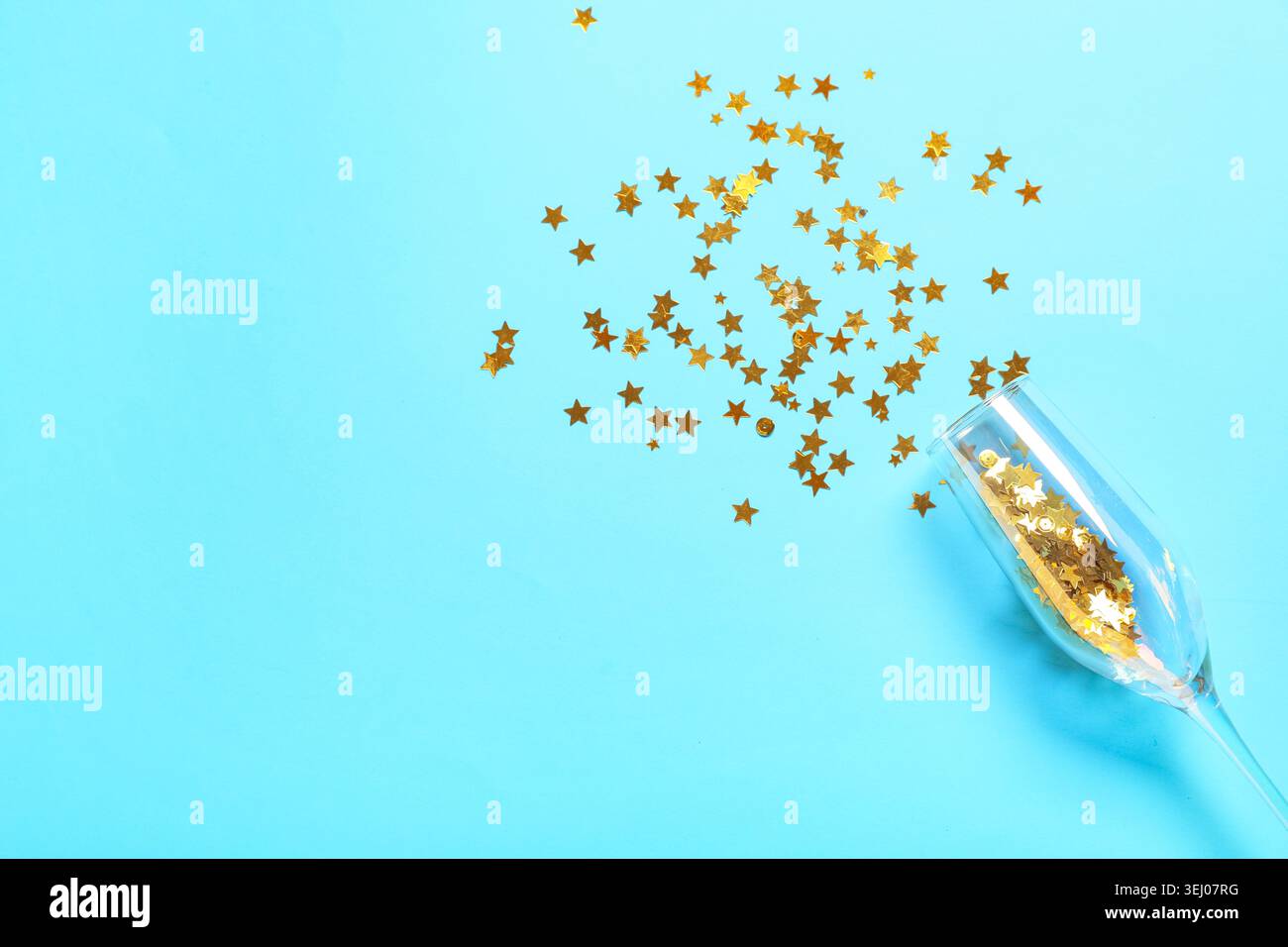 Champagne glass with beautiful golden confetti in shape of star on blue ...