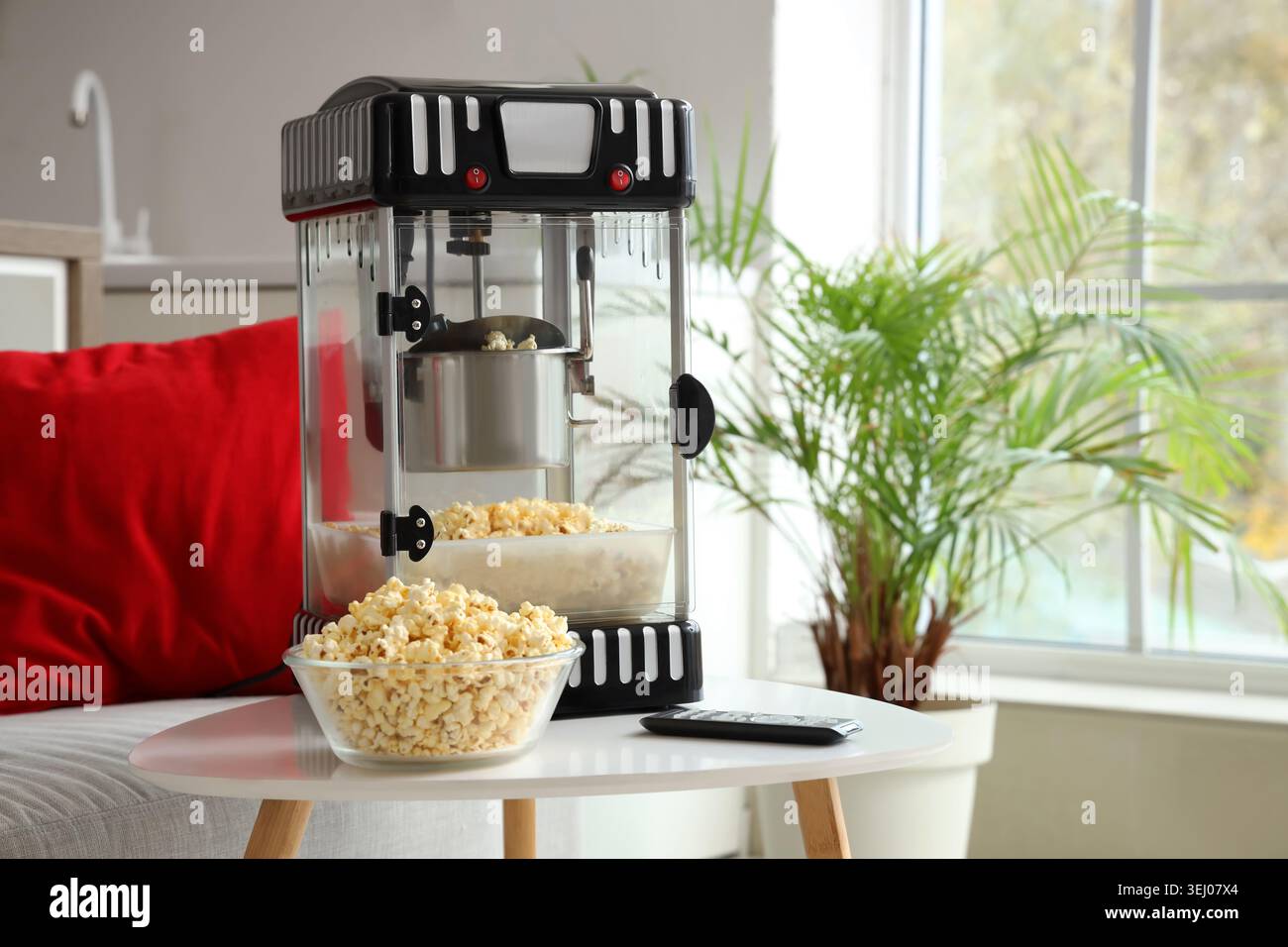 Modern popcorn machine and TV remote on coffee table in living room ...