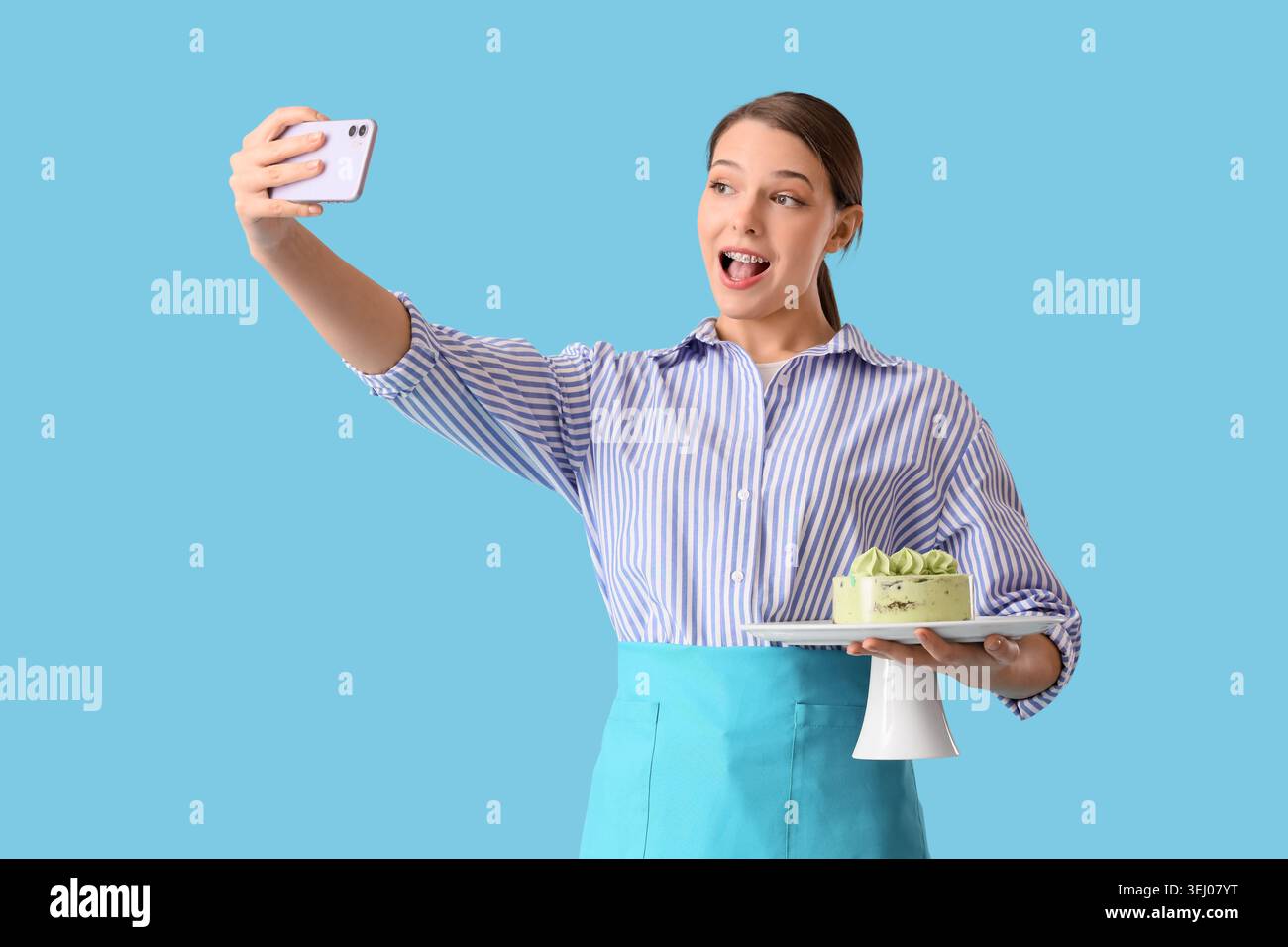 Female confectioner with cake taking selfie on blue background Stock ...