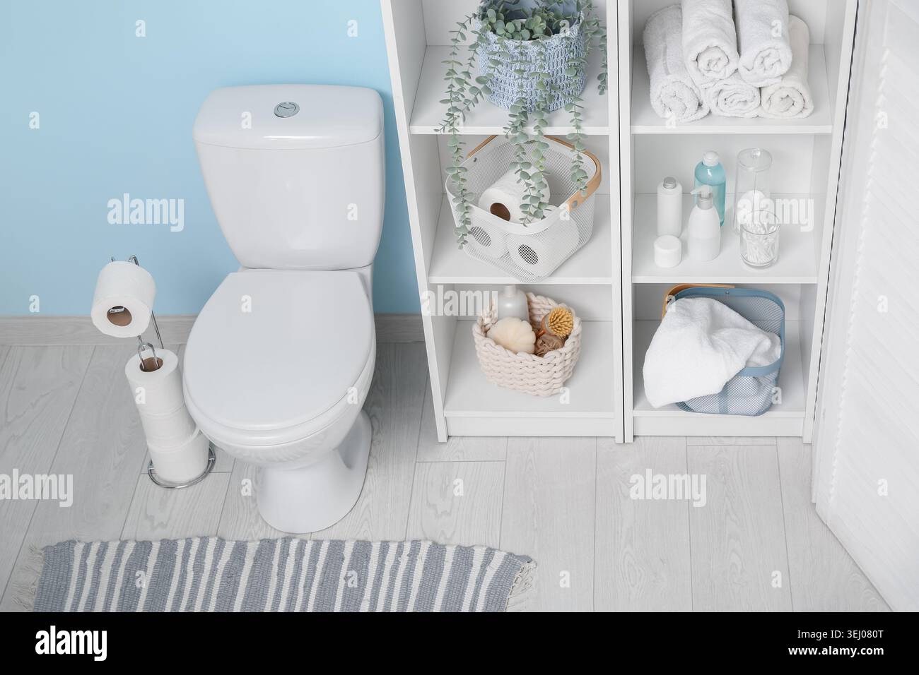 Interior of restroom with toilet bowl and shelving unit near blue wall ...