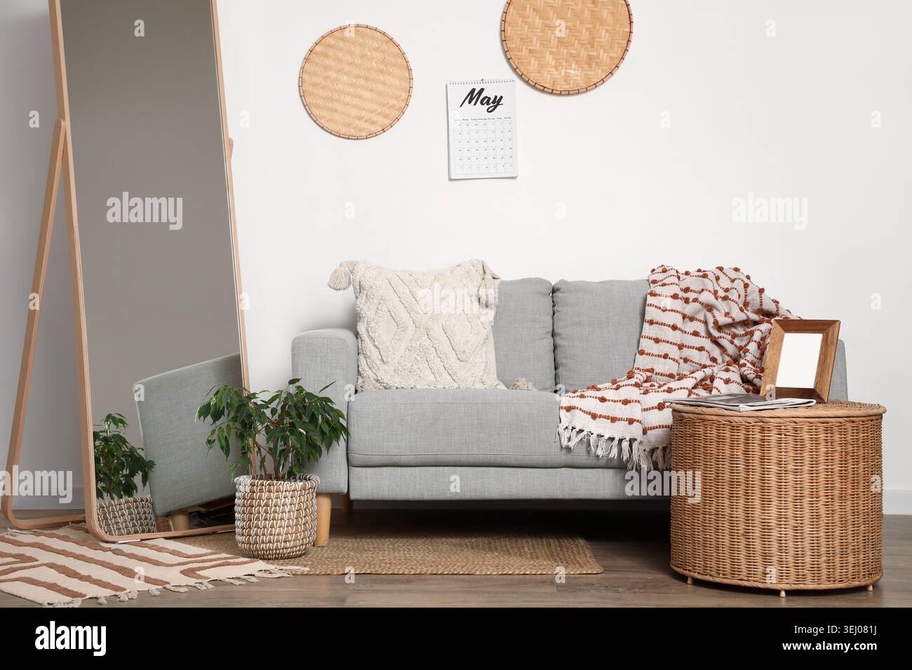 Sofa, table and floor mirror near white wall in interior of room Stock ...