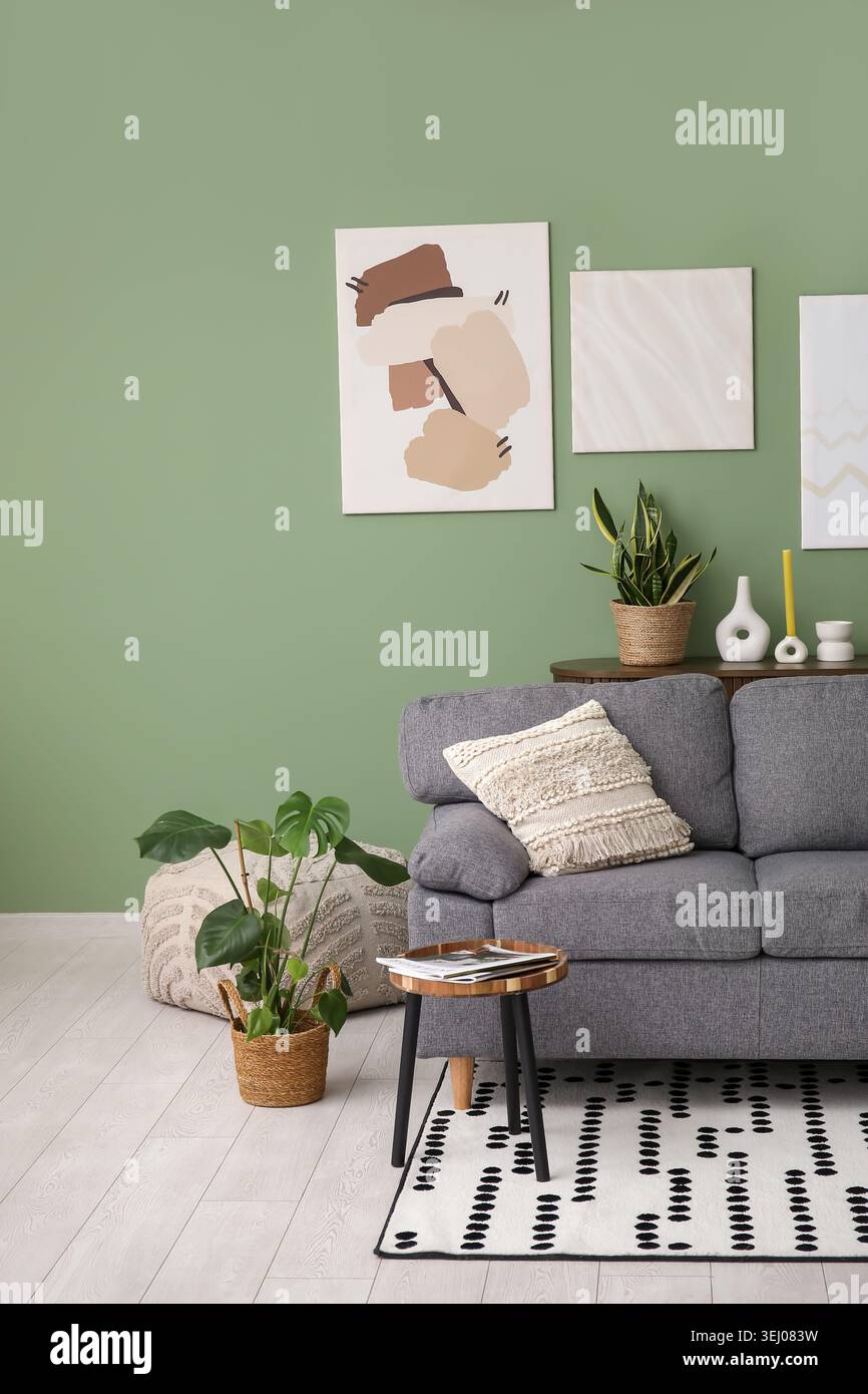 Comfortable sofa, coffee table, pictures and houseplants in interior of ...