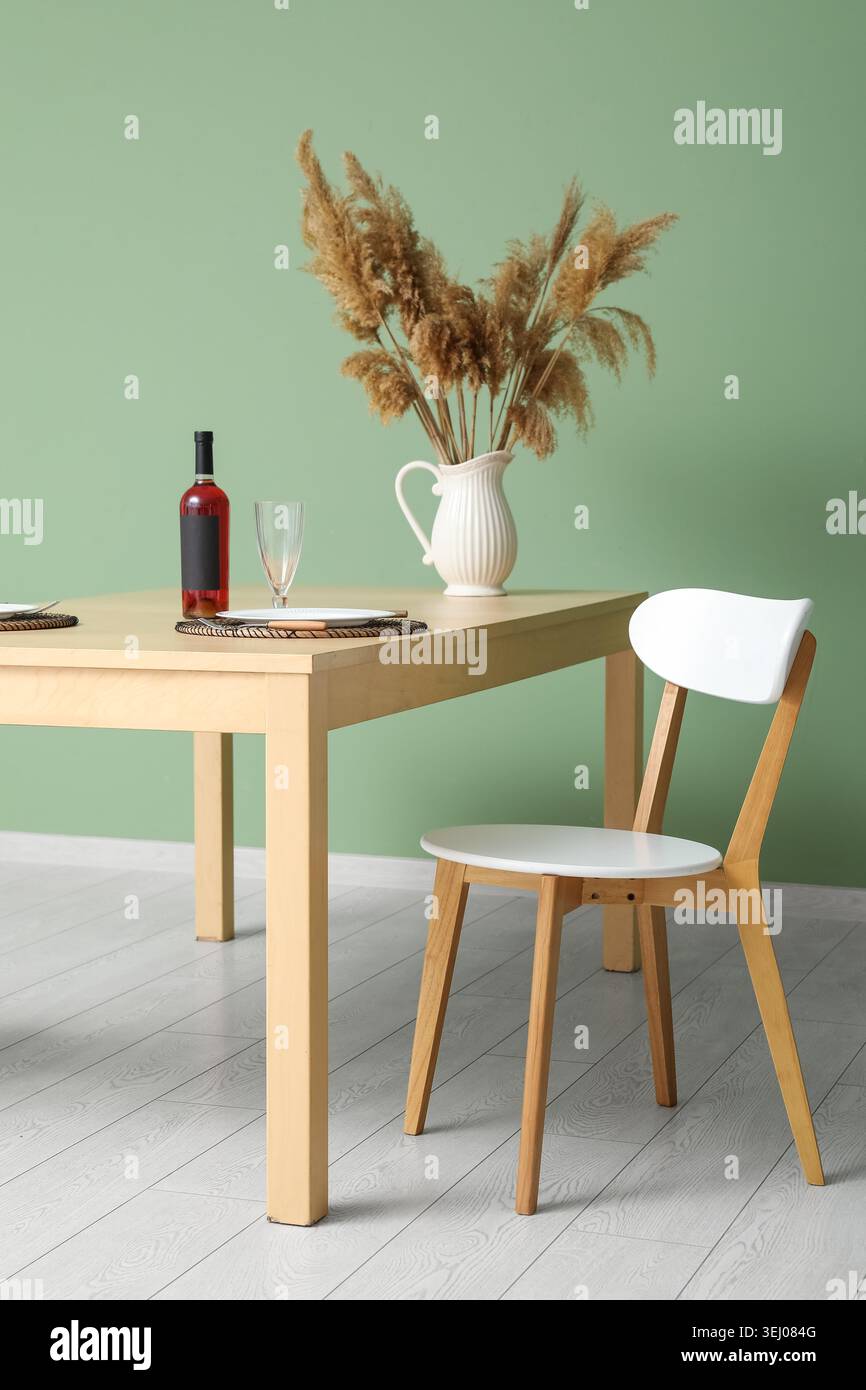Dining table, vase of pampas grass and wine bottle in room Stock Photo ...