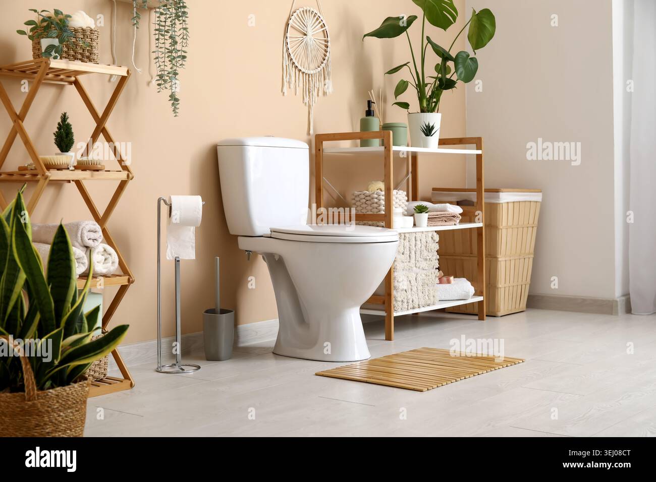 Toilet bowl, shelving units and laundry basket near beige wall in ...
