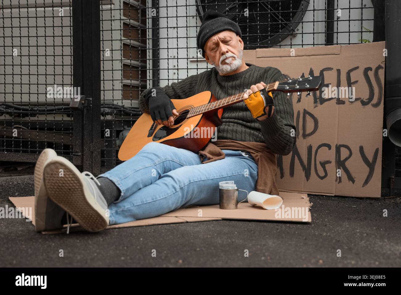 Mature homeless man playing guitar on street Stock Photo - Alamy
