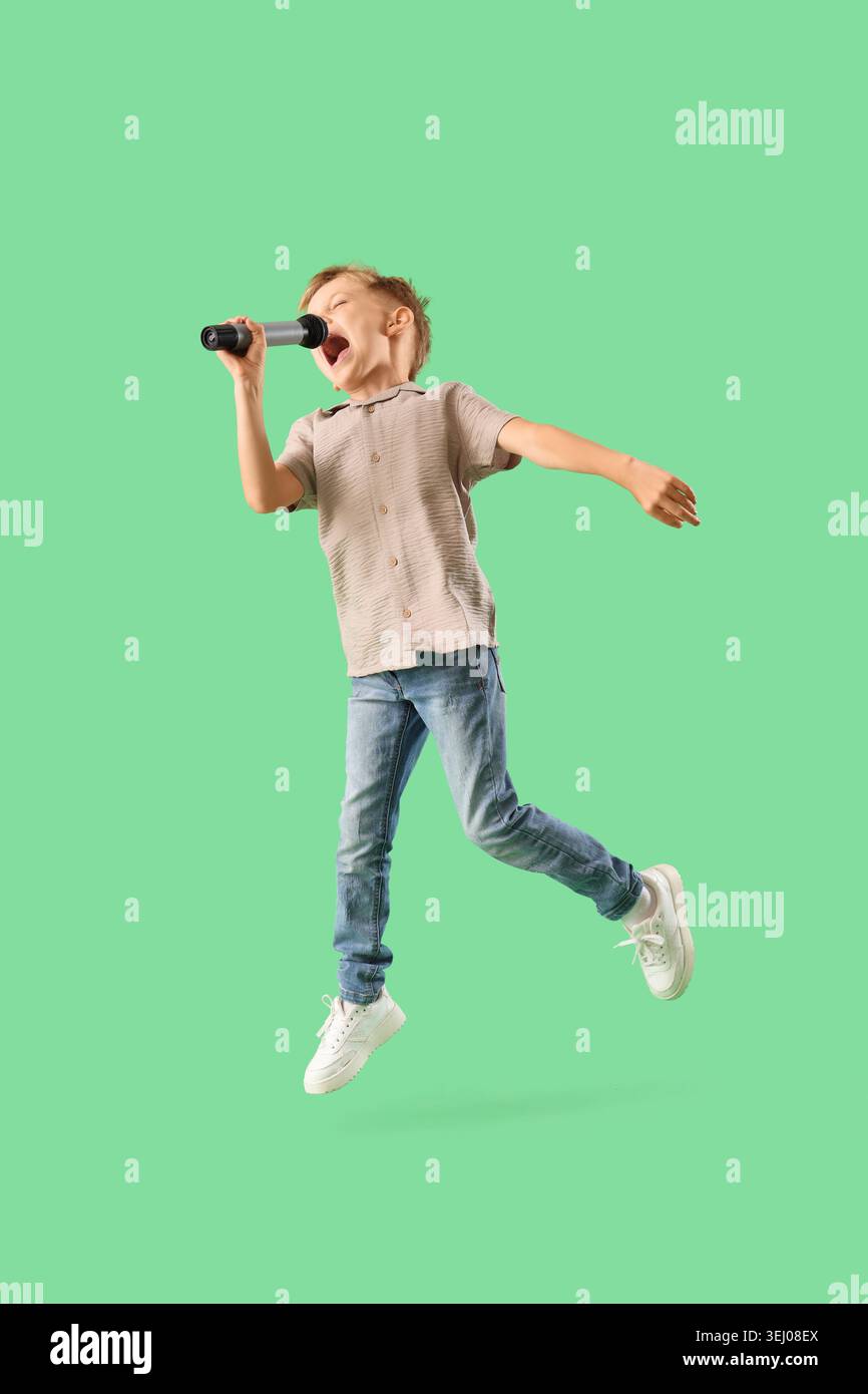 Cute little boy with microphone singing on green background Stock Photo ...