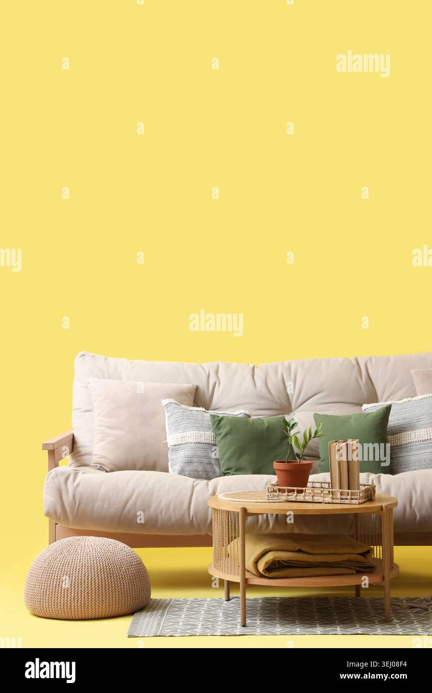 Comfortable white sofa and wooden coffee table with books on yellow ...