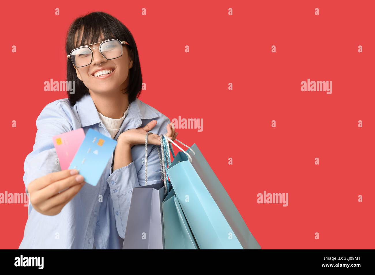 Beautiful young woman with credit cards and shopping bags on red ...