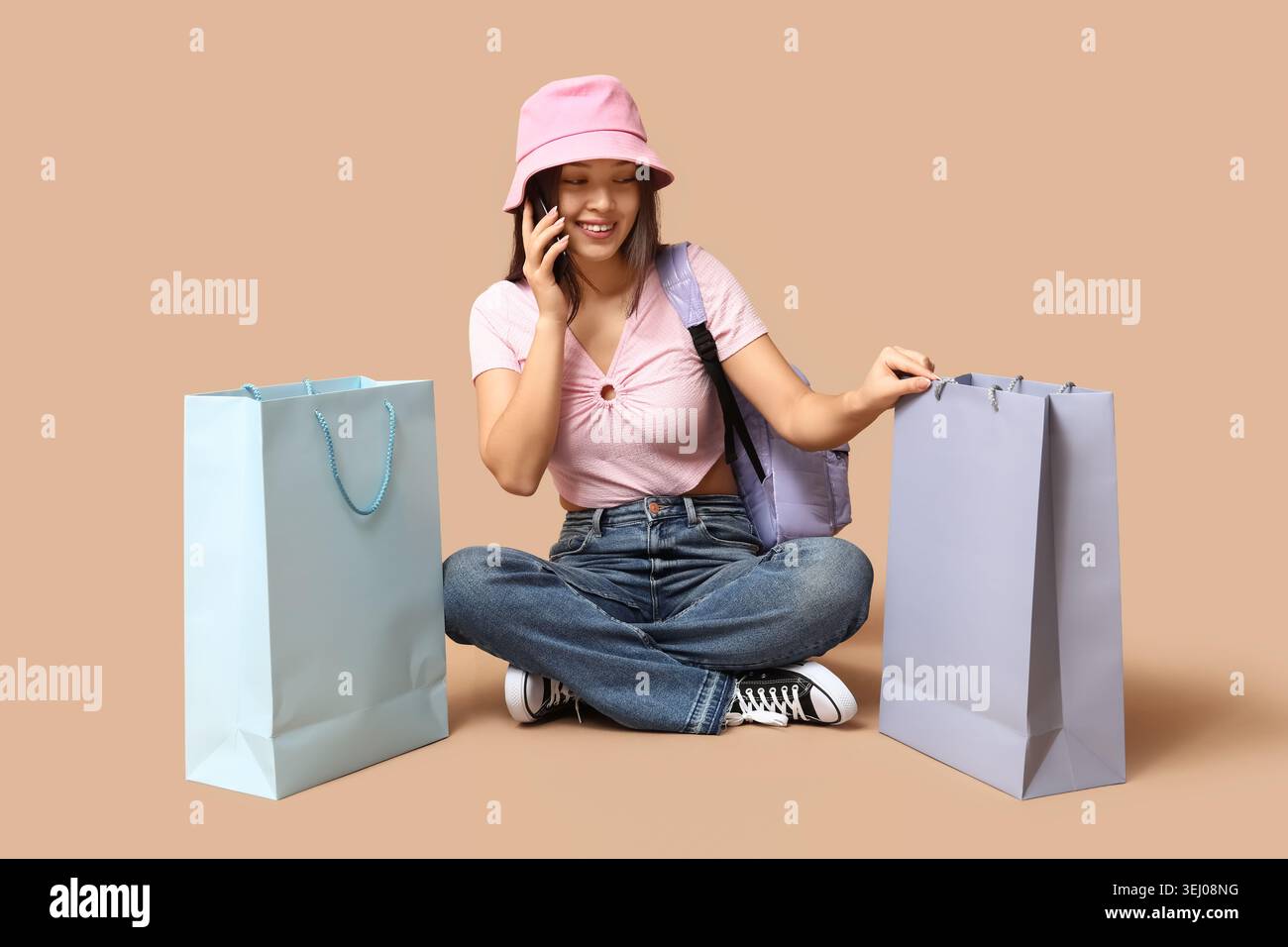 Fashionable young Asian woman in stylish jeans with shopping bags ...