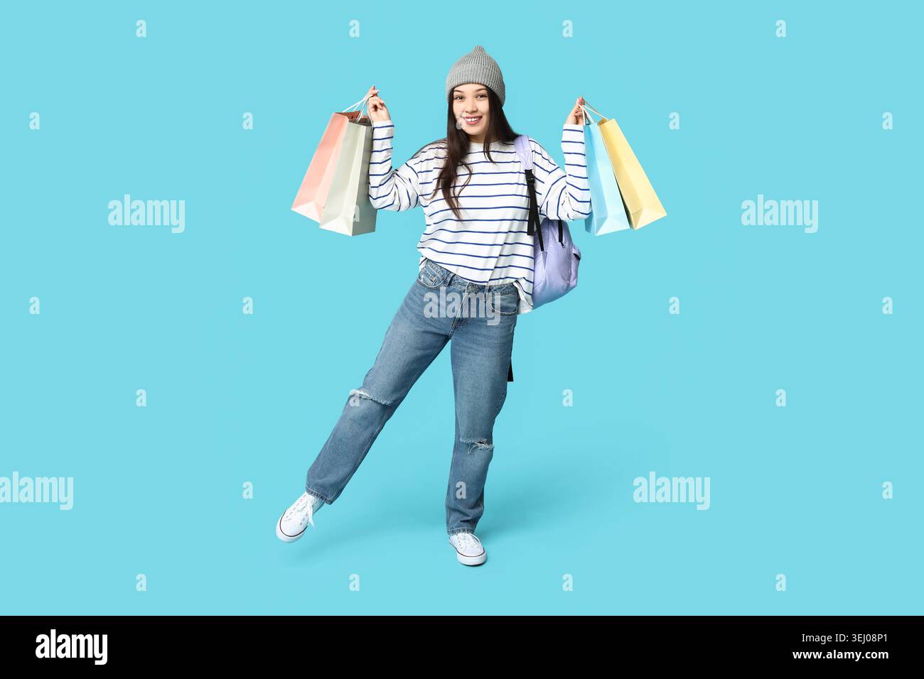 Fashionable young Asian woman in stylish jeans with shopping bags on ...