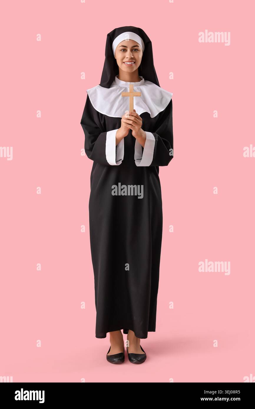Young nun with cross on pink background Stock Photo - Alamy