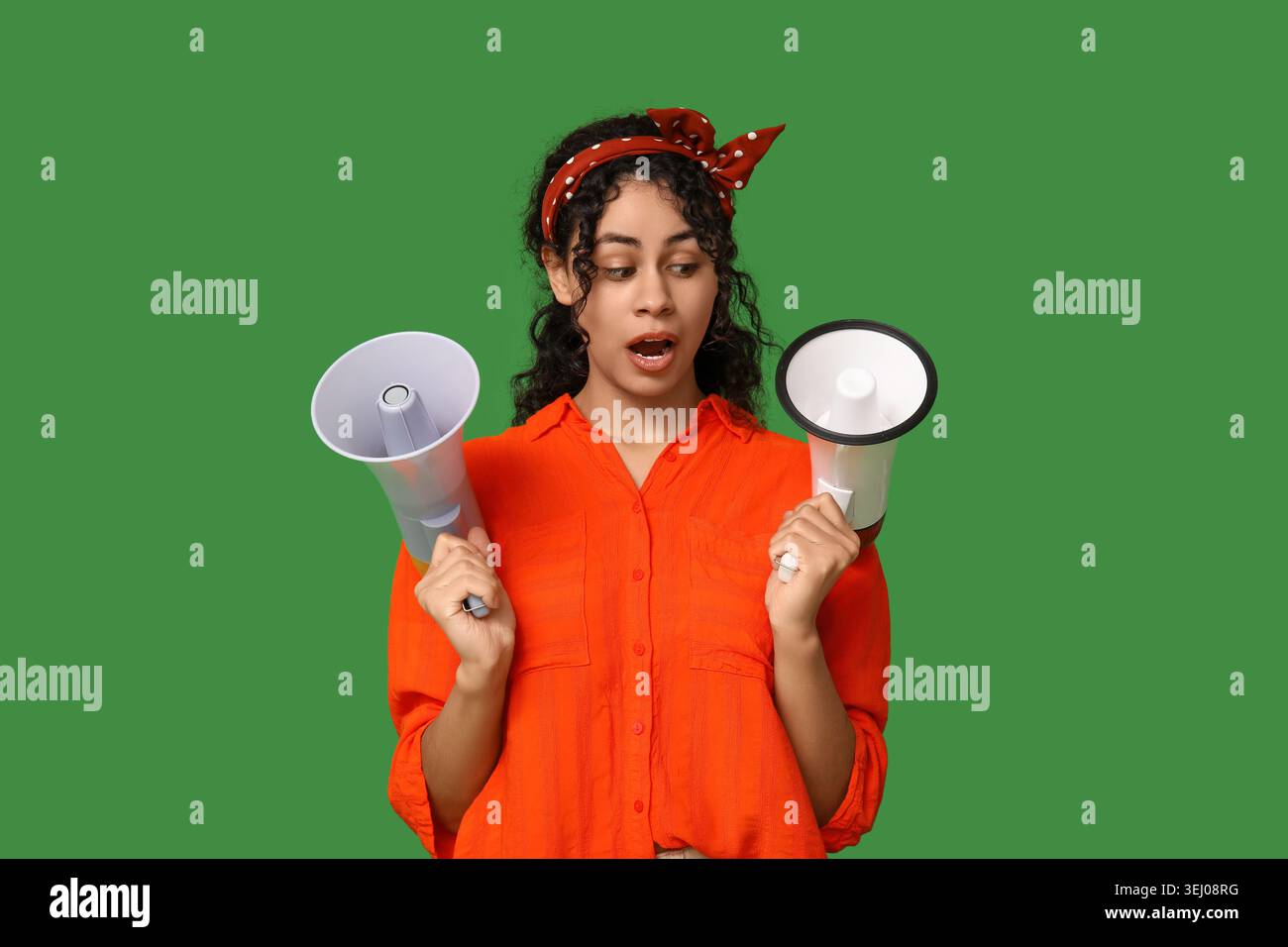 Surprised African-American woman with megaphones on green background ...