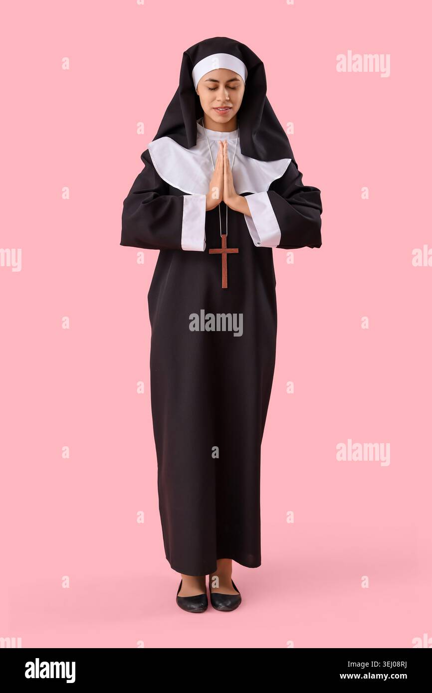 Young nun praying on pink background Stock Photo - Alamy