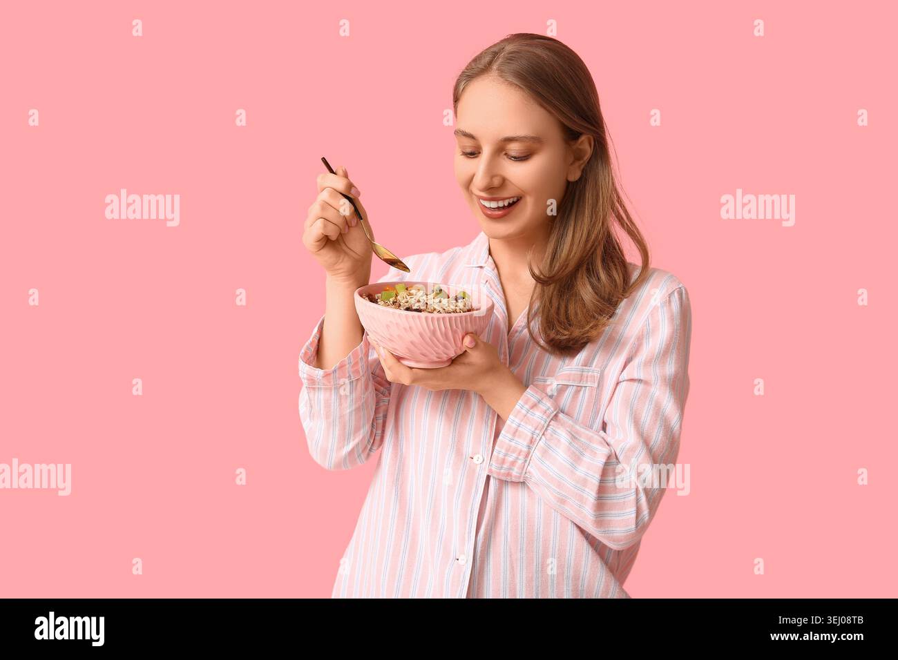 Young woman eating healthy oatmeal on pink background Stock Photo - Alamy