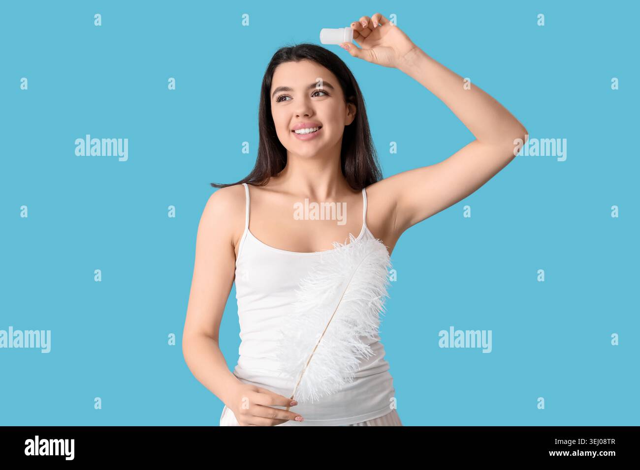 Happy smiling young woman with crystal deodorant and feather on blue ...