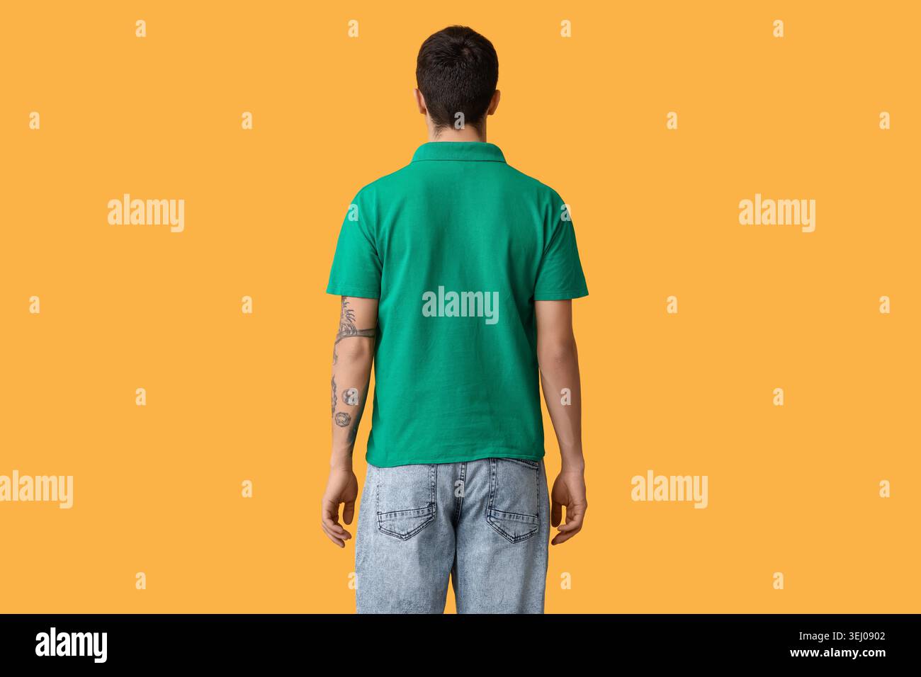 Handsome young man in stylish green t-shirt on yellow background, back ...