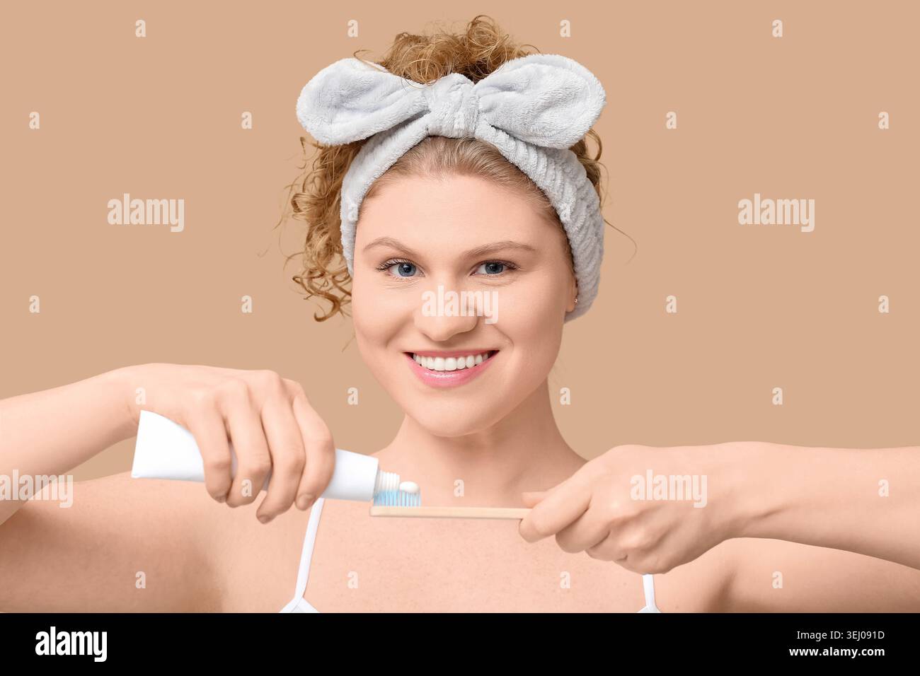 Beautiful young happy woman with toothbrush and paste on brown ...