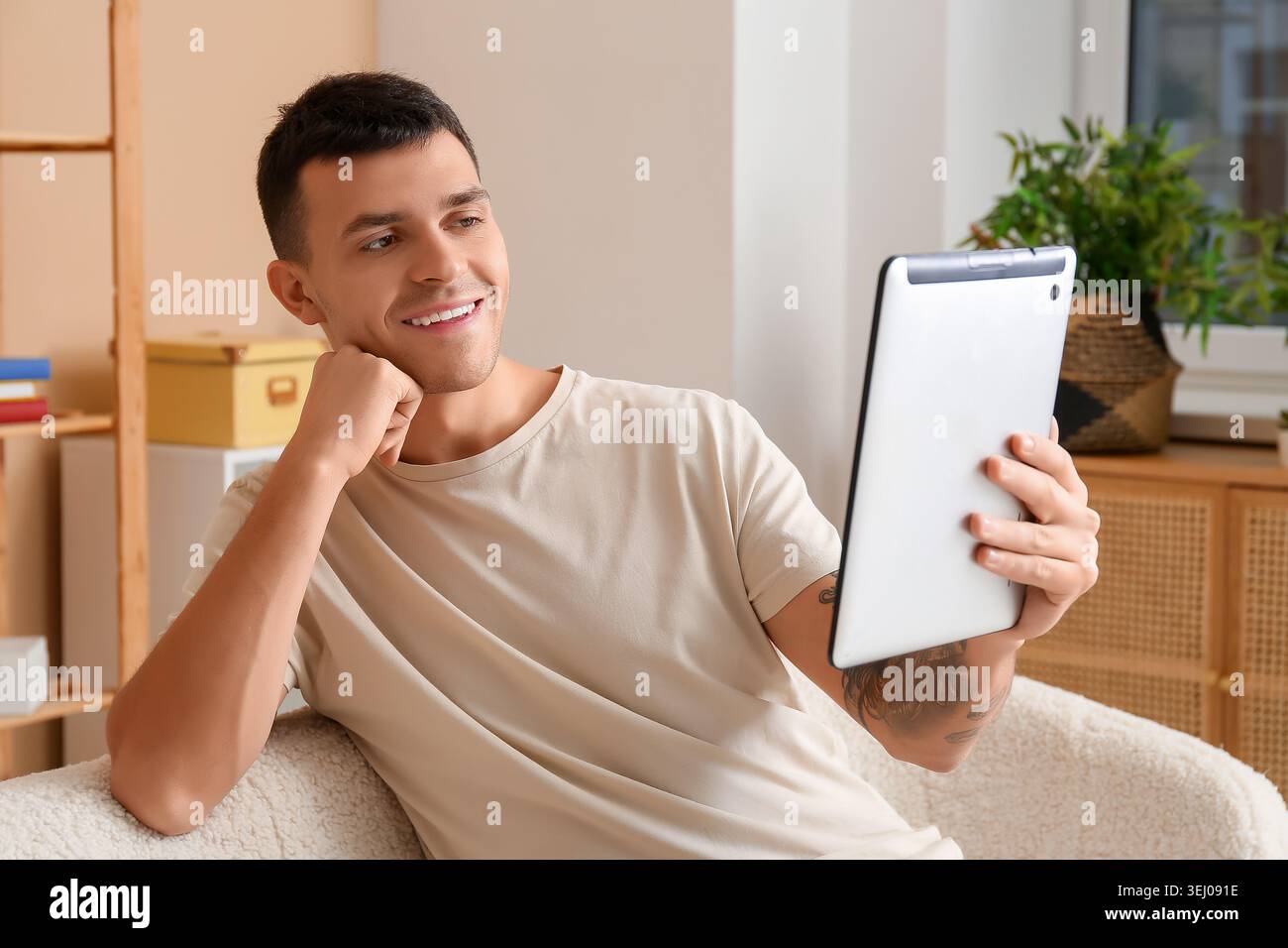 Young man with tablet computer video chatting on online date at home ...
