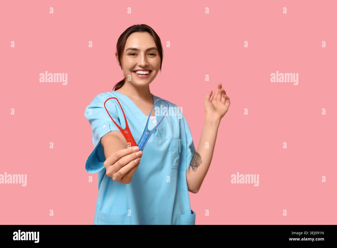 Young female dentist with tongue scrapers on pink background Stock ...