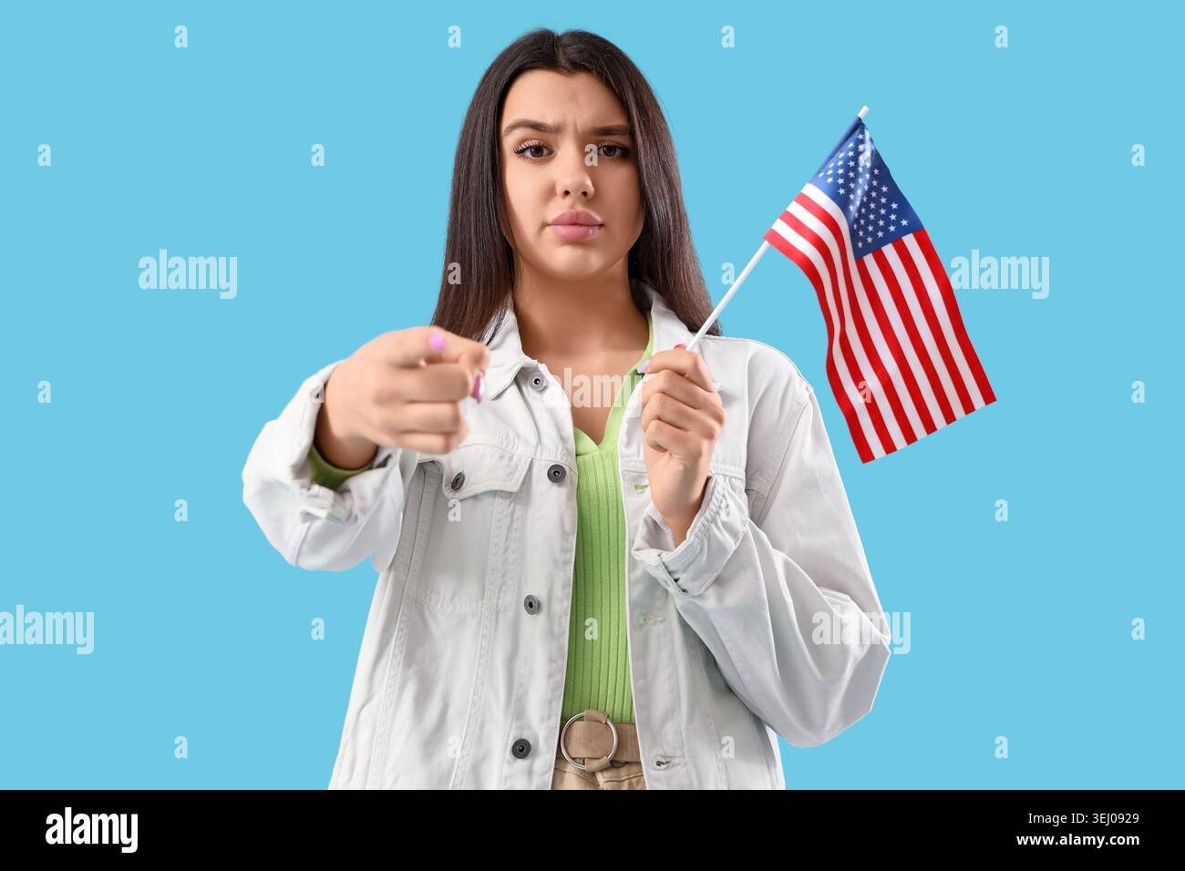 Young woman with USA flag pointing at viewer on blue background ...