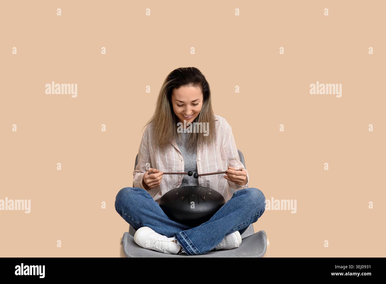Beautiful mature woman with sticks playing glucophone and sitting on ...