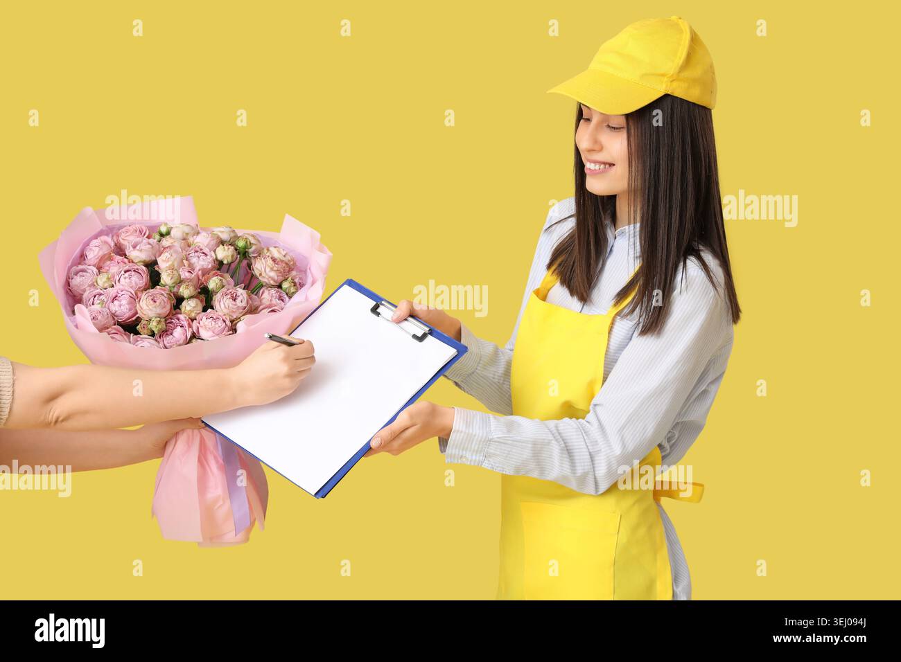 Young delivery woman giving bouquet of beautiful roses on yellow ...