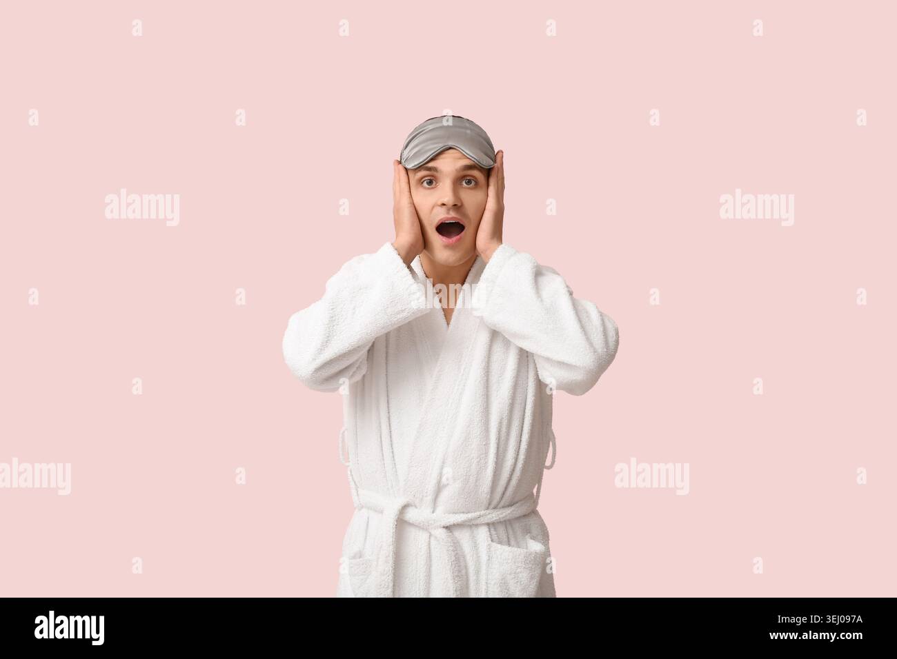Portrait of shocked young man in bathrobe on pink background Stock ...