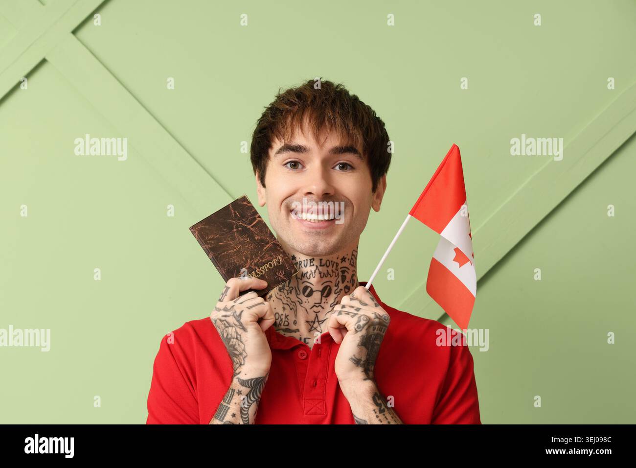 Handsome young man with flag of Canada and passport on green background ...