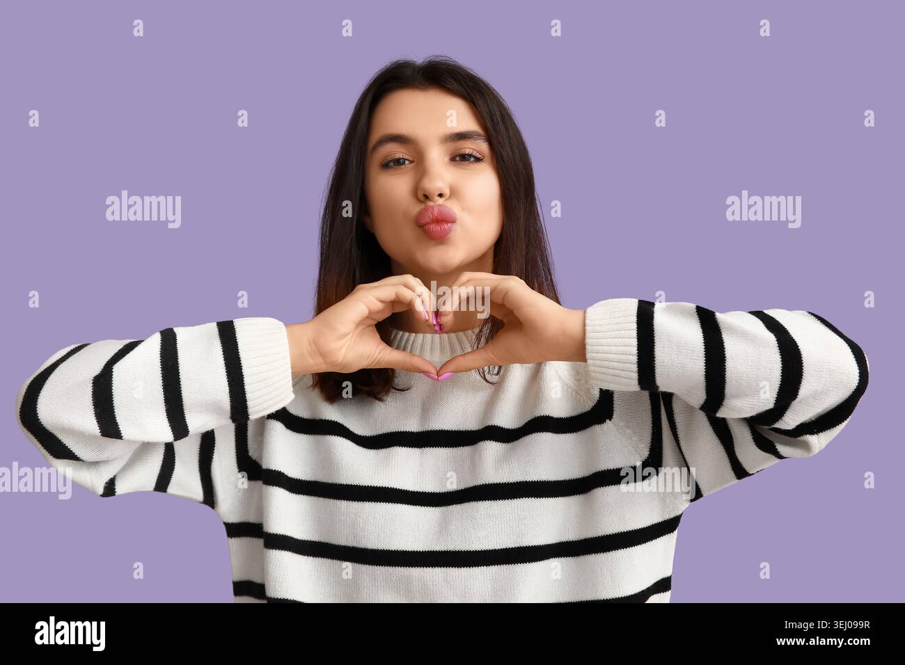 Beautiful young girl showing heart gesture on purple background ...