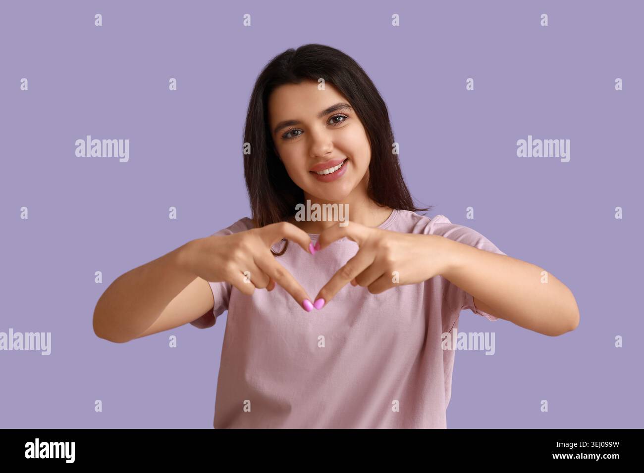 Happy young girl showing heart gesture on purple background. Valentine ...
