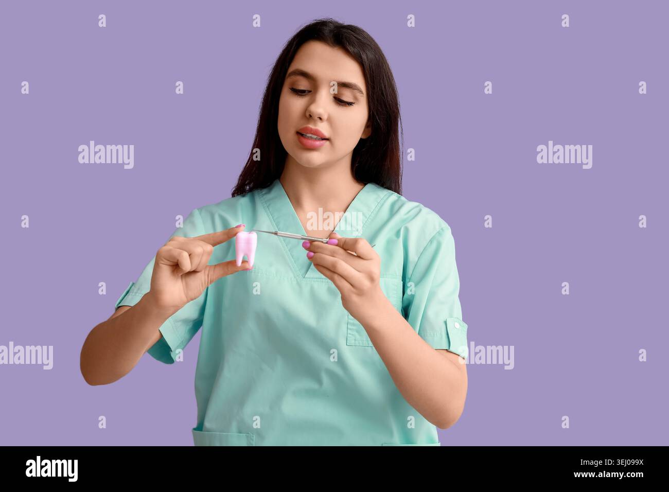 Female dentist with tool and plastic tooth on purple background. World ...